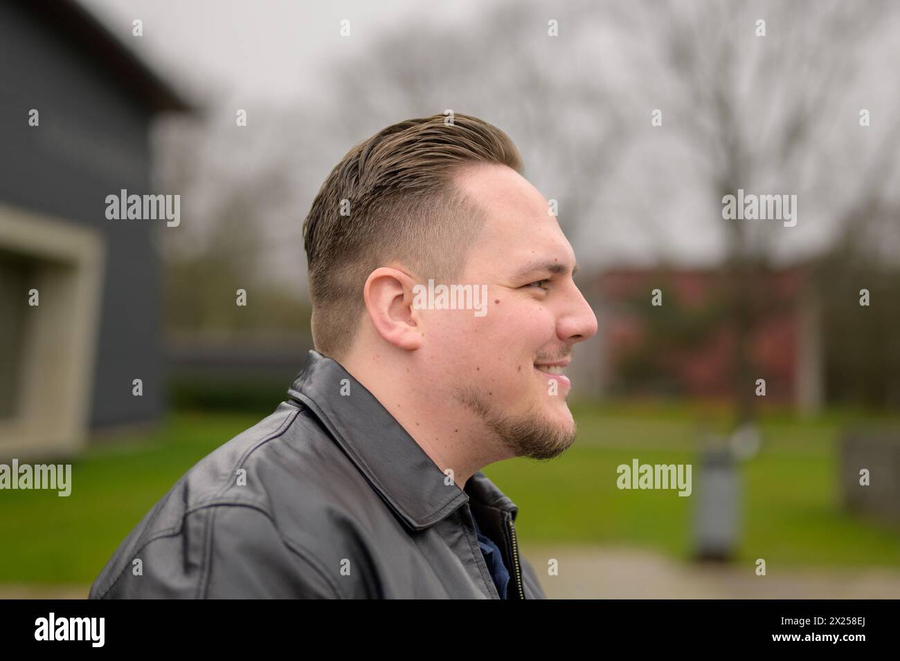 Side view of a young attractive man in his twenties looking friendly to ...