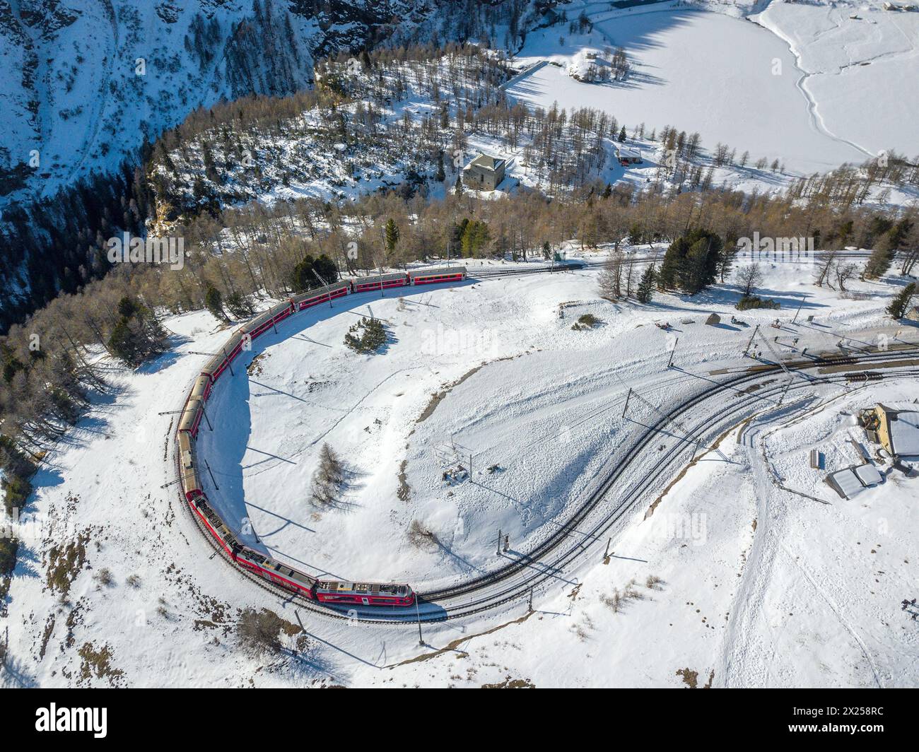 Aerial image of a red train passing on the Rhaetian Railway track with ...