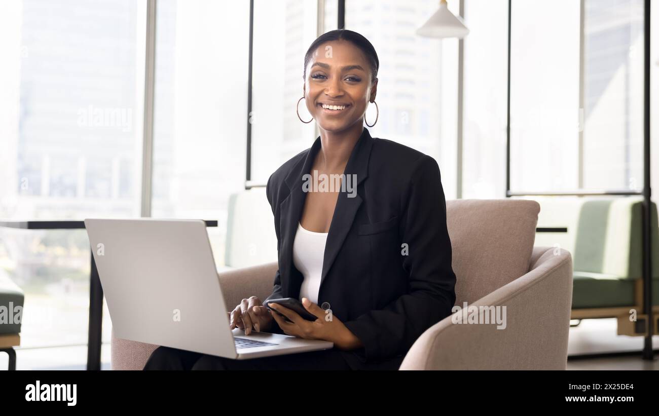 Happy African American professional woman in formal suit holding laptop ...