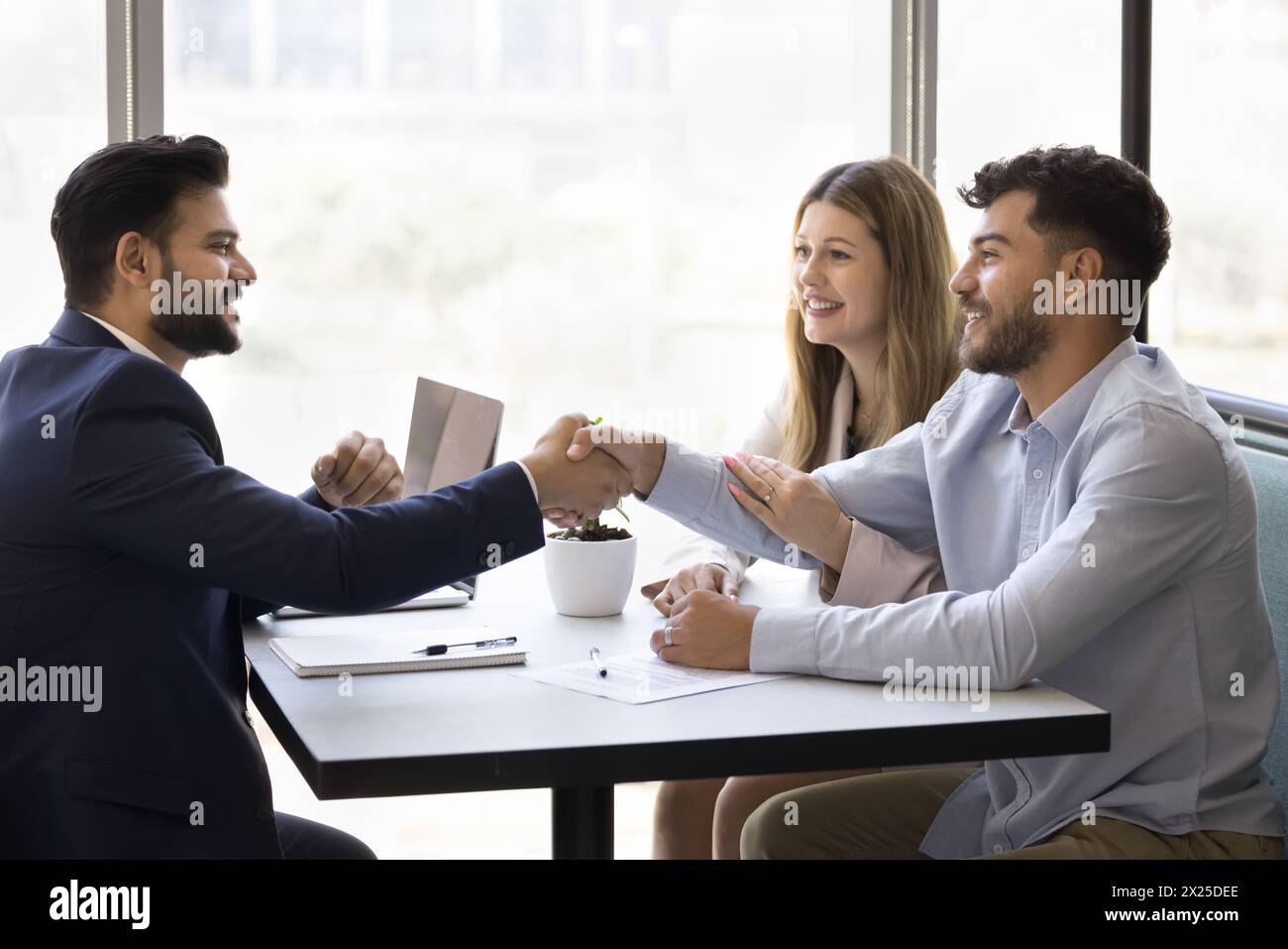 Happy young diverse couple shaking hands with Indian consultant Stock ...