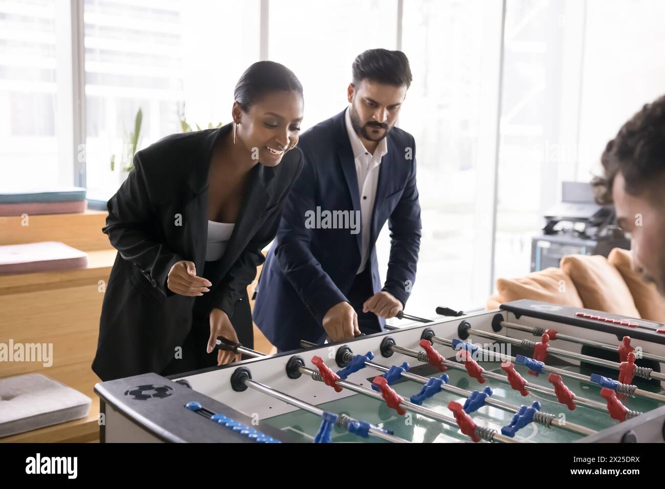 Positive excited young multiethnic couple of professionals playing toy ...