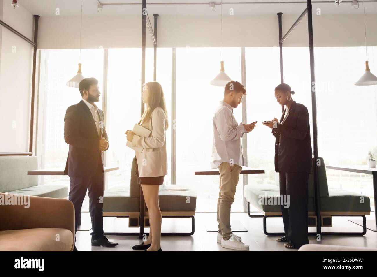 Two multiethnic couples of office colleagues discussing work projects ...
