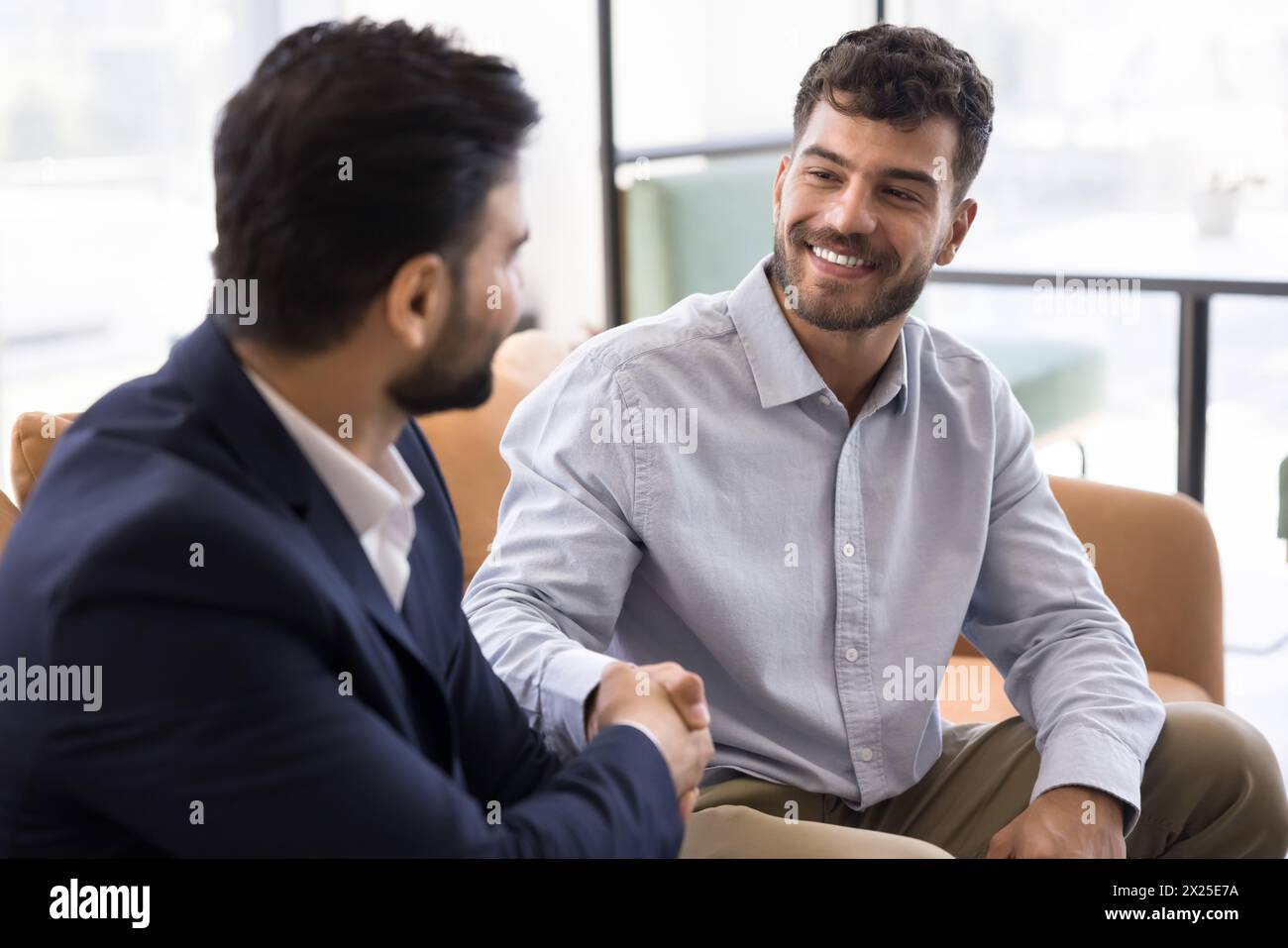 Happy young Arab business customer giving handshake to Indian manager ...