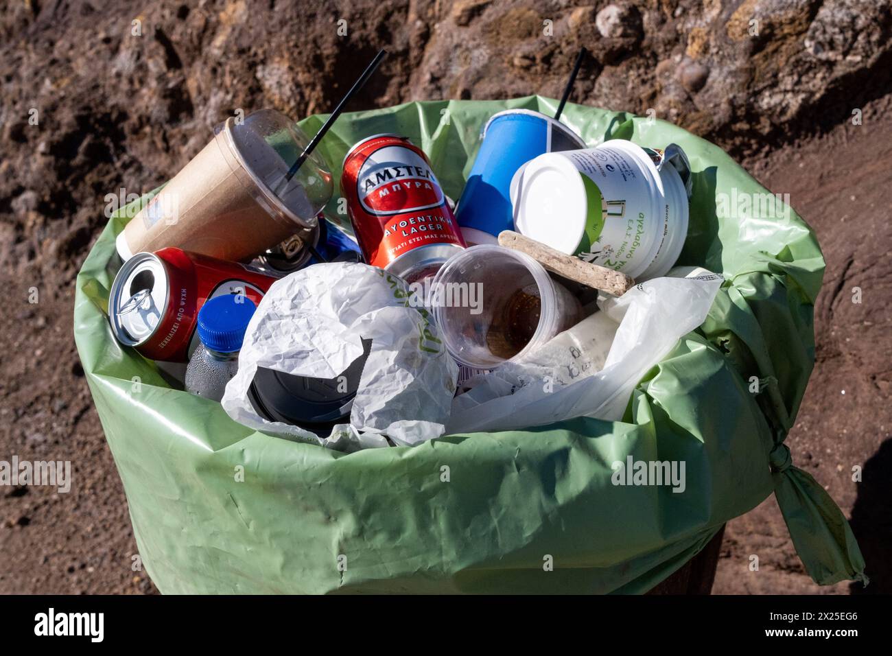 A rubbish bin overflowing with single-use plastic waste, cans and ...