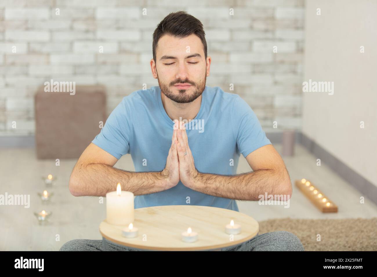 man meditating in prayer position by lit candles Stock Photo - Alamy