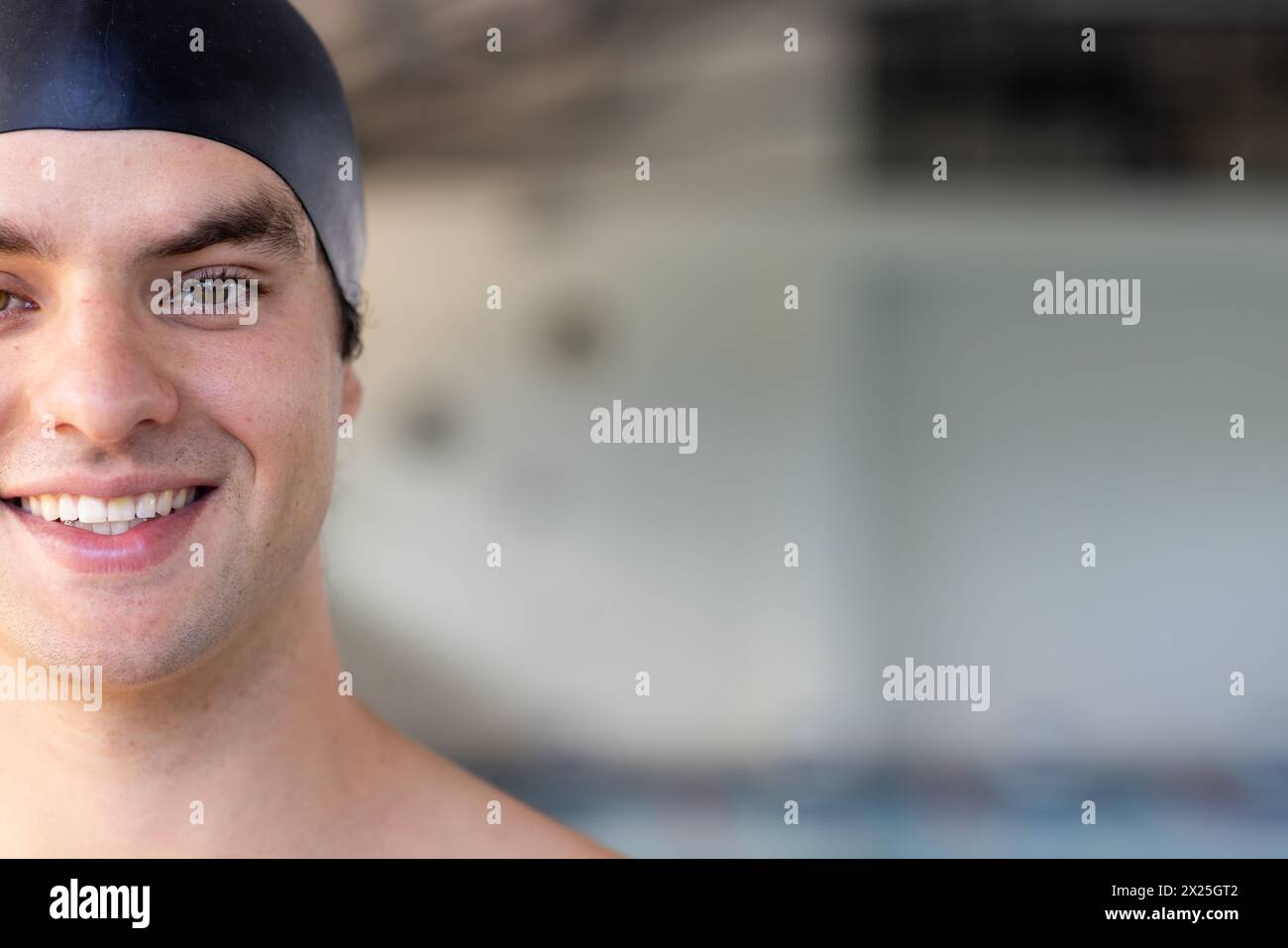 Caucasian young male swimmer standing indoors, wearing black swim cap ...