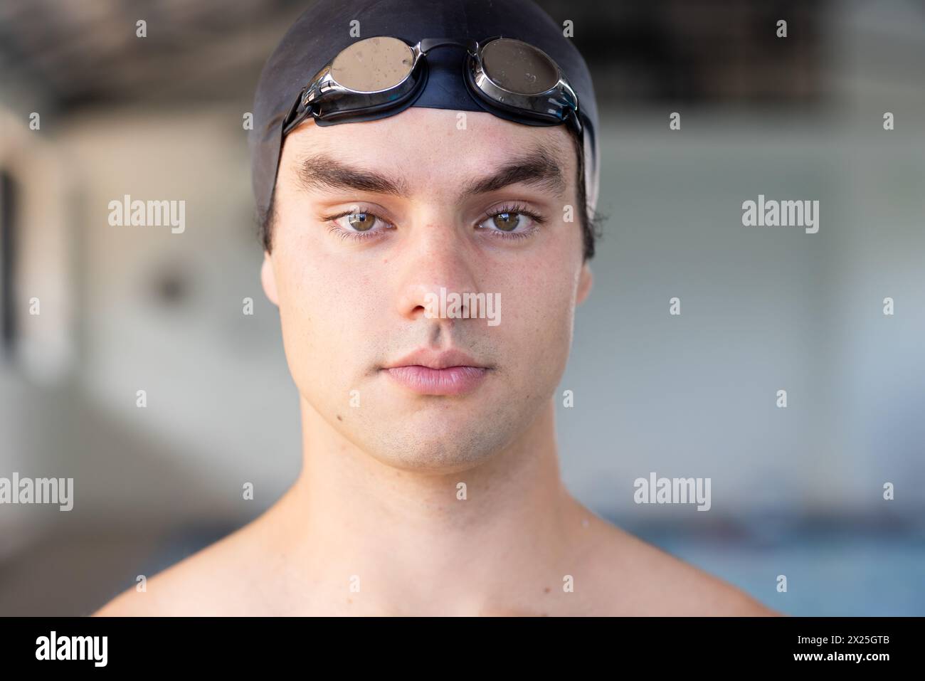 Caucasian young male swimmer wearing goggles preparing for training ...