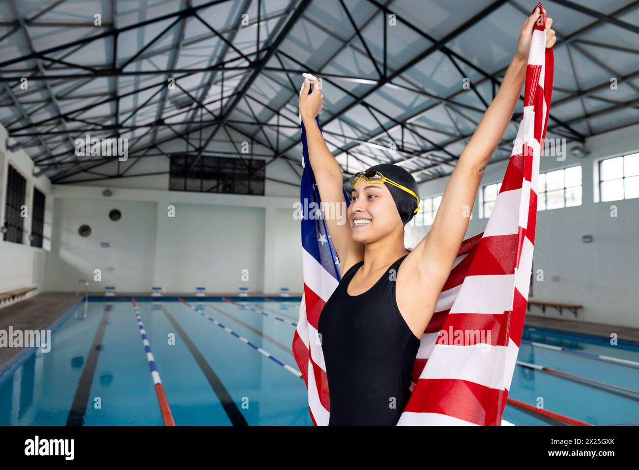 A biracial young female swimmer holding an American flag stands ...