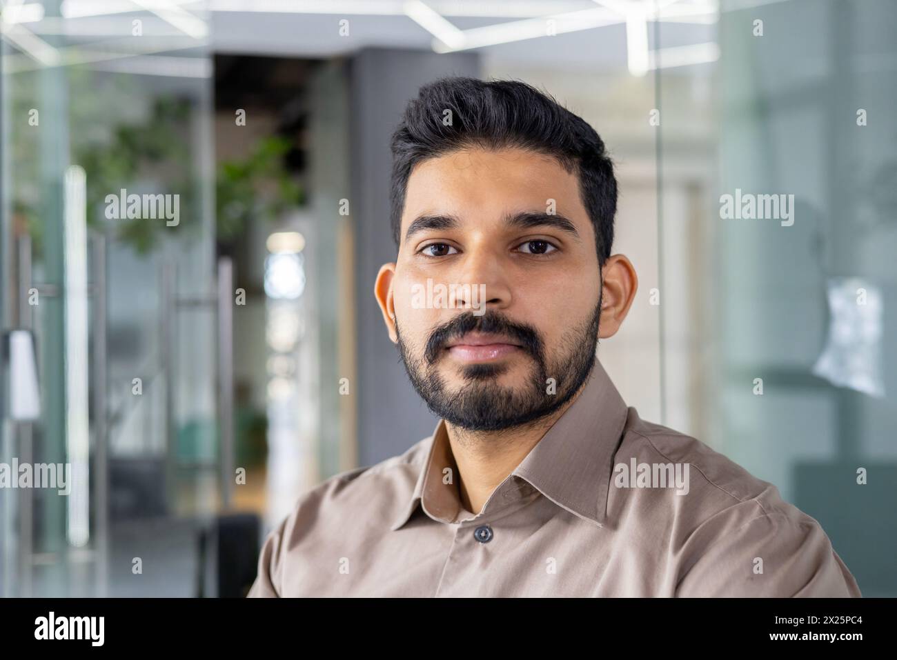 A portrait of a young, confident professional man with a beard in a ...