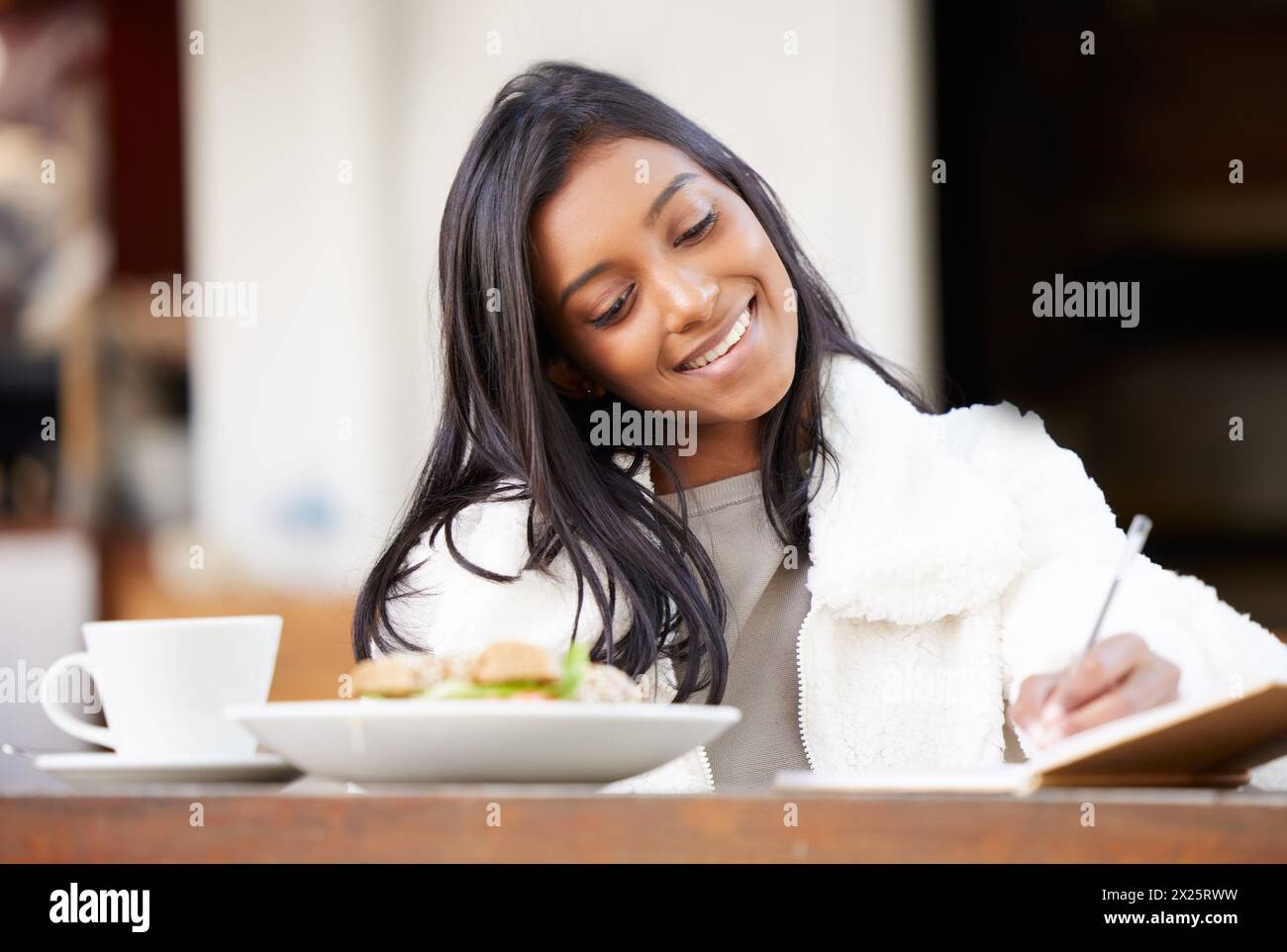 Woman, writer and notebook at lunch in restaurant with smile, thinking ...