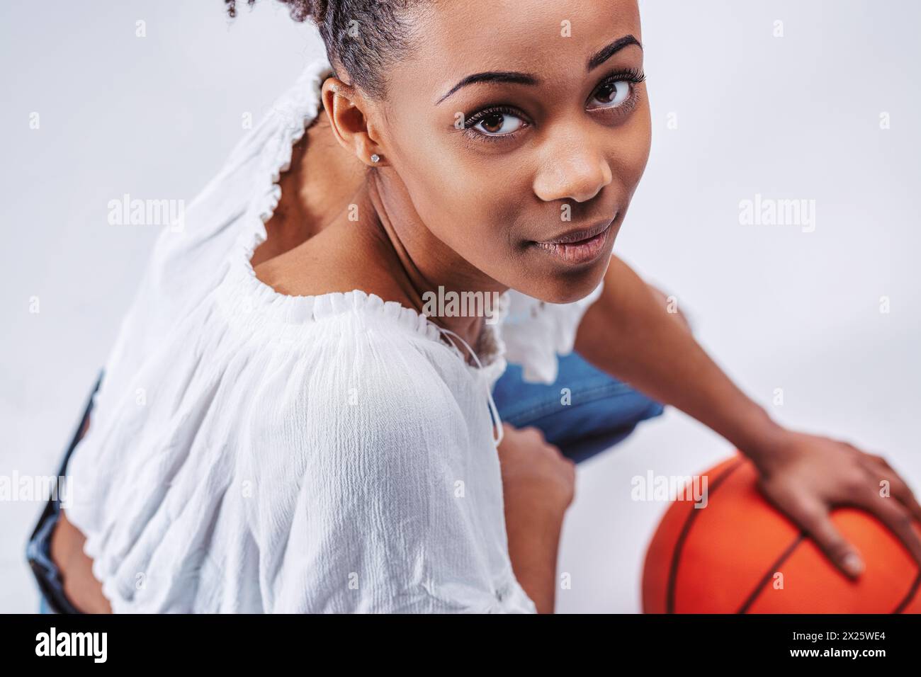 Young, athletic woman gripping a basketball, her determined gaze ...