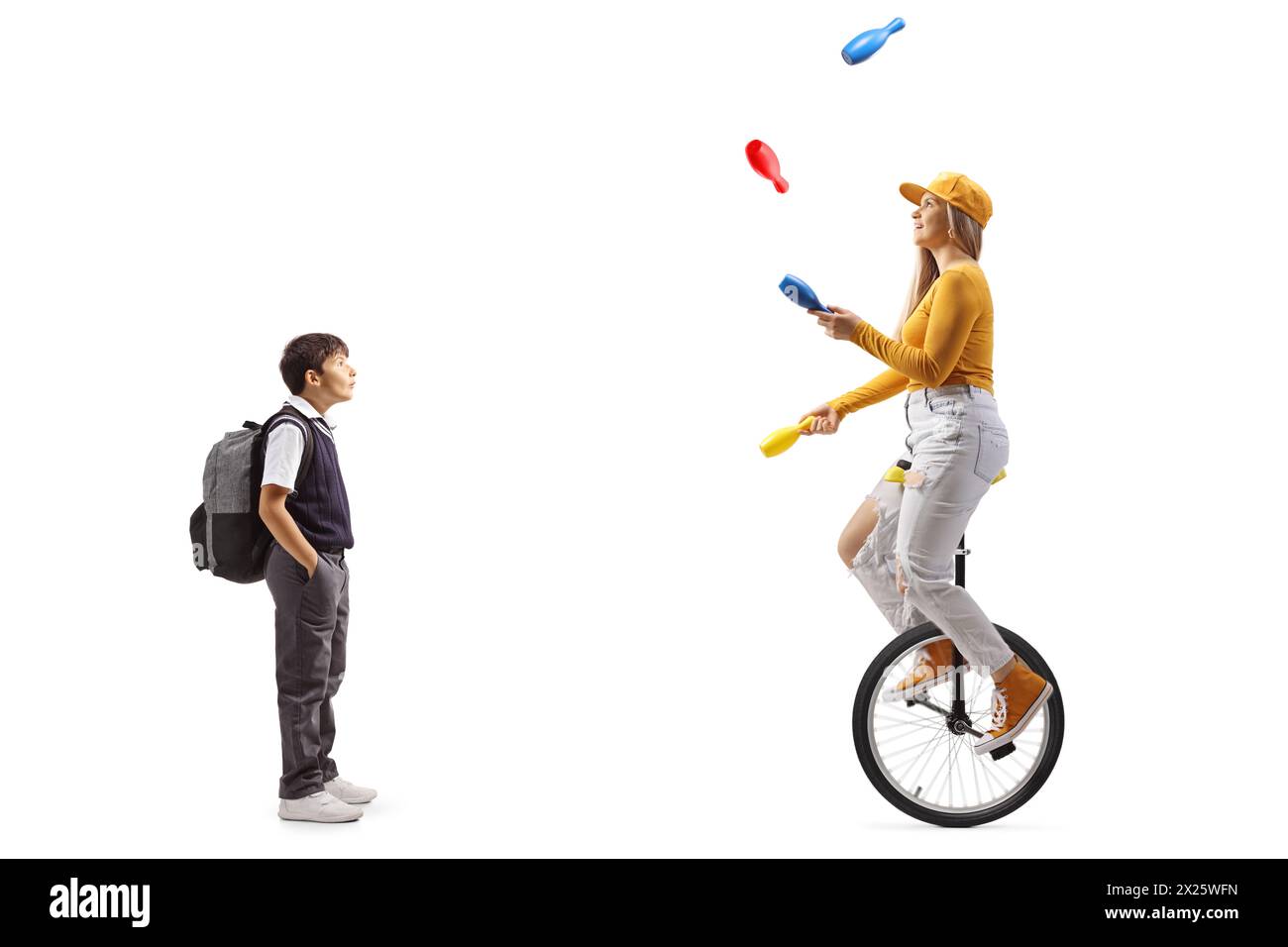 Surprised schoolboy standing and watching a female riding a mono cycle ...