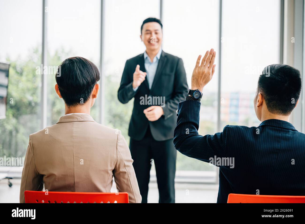 At a corporate event, a diverse audience of businesspeople raises their ...