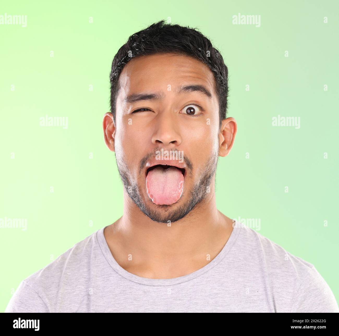 Man, portrait and silly in studio, tongue and goofy comic or funny face ...