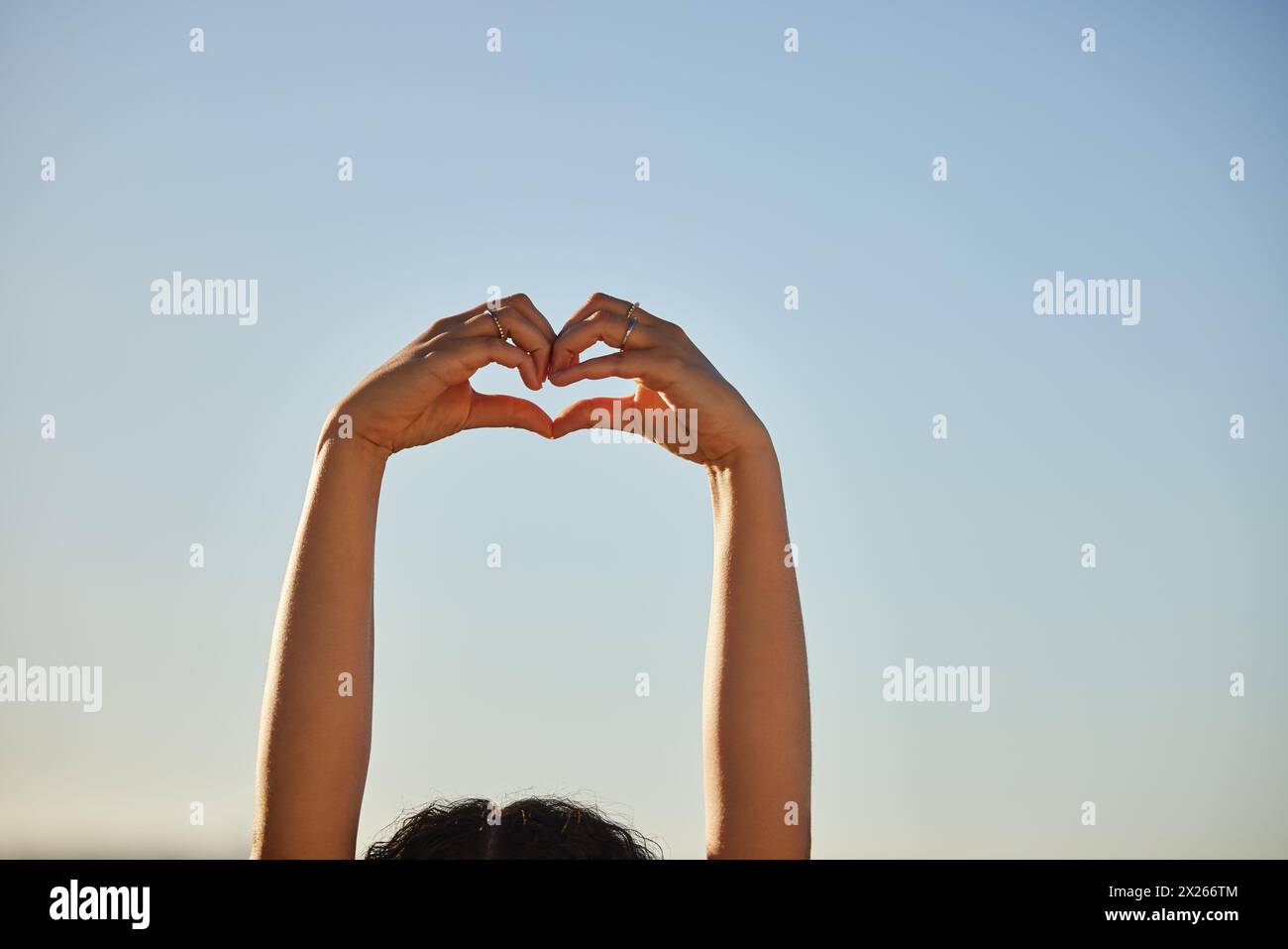 Person, heart hands and sign for love on sky background, charity or ...
