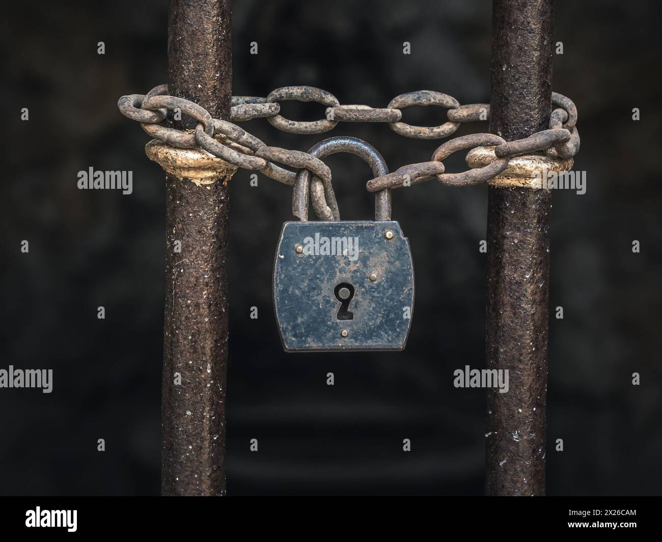 Vintage old rusty padlock with chains on an iron barred gate, dark ...