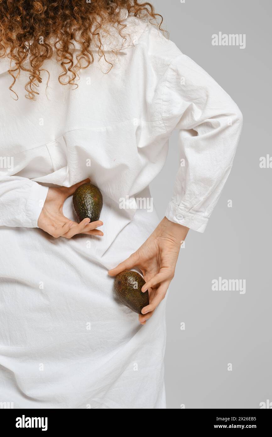 Female hands hold two whole avocado behind her back Stock Photo - Alamy