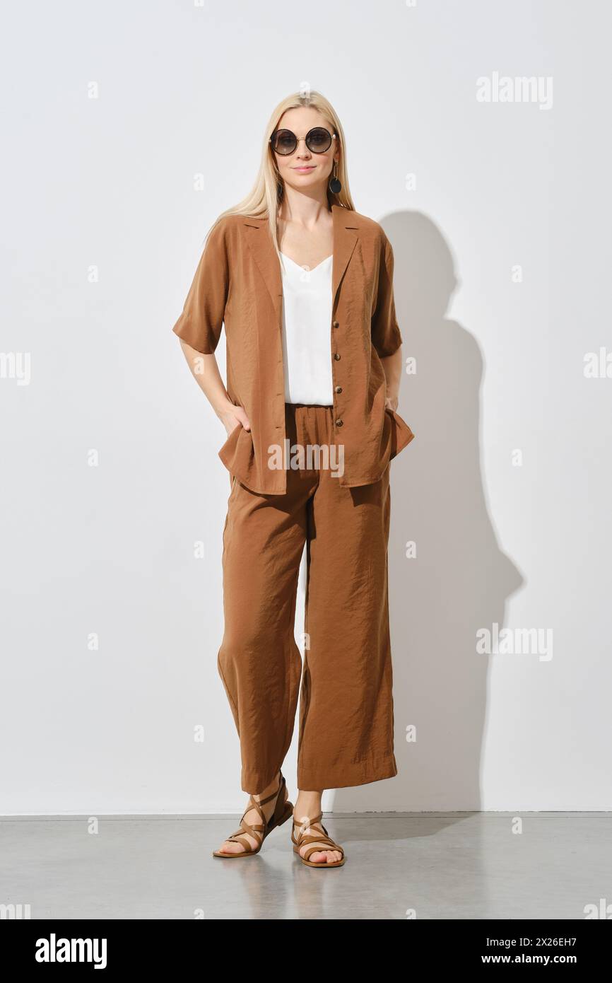 Cheerful blonde woman showcases a modern summer casual outfit. The ...