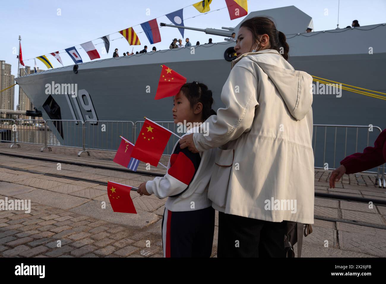A child carries Chinese national flags and the Chinese Navy flag near ...