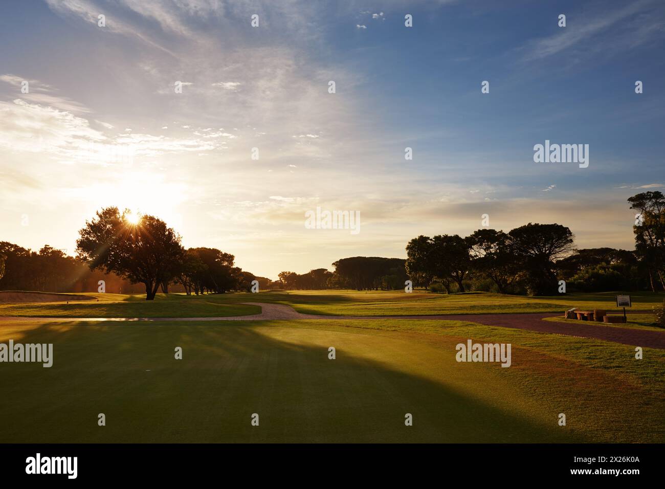 Grass, sunset sky and trees on golf course with clouds, shadow and ...