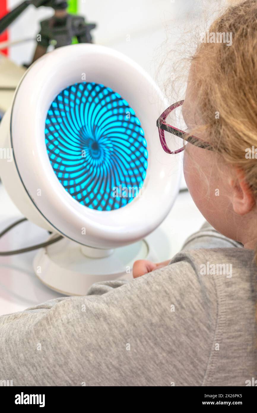 A girl is sitting in front of a device for stimulating vision ...