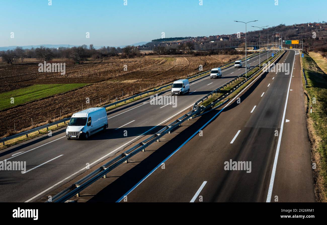 Four delivery vans in line on a highway. Van light transportation on a ...