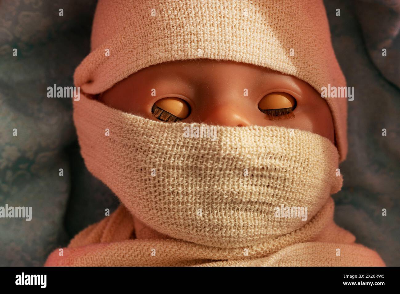 The doll the baby is wound with fabric. The body of the child is ...