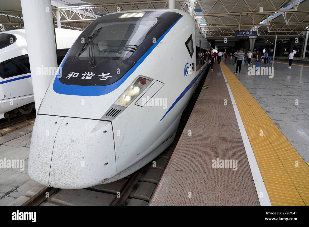 Express train CRH380 to Yichang, A high-speed train waits at a platform with passing passengers ...
