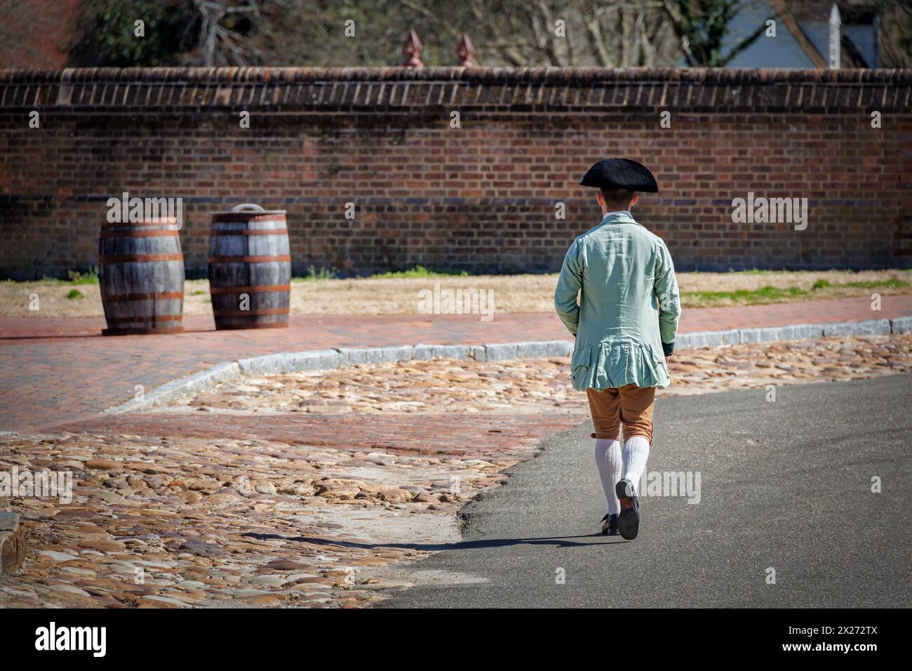 A man walks down the street, in period clothing, at Colonial ...