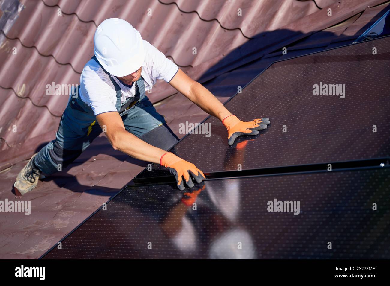 Worker building solar panel system on rooftop of house. Man engineer in ...