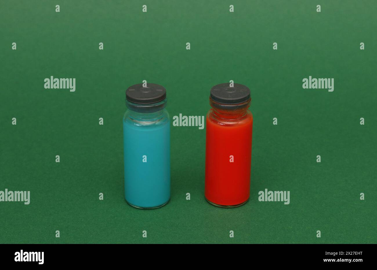 Two ampoules with red and blue chemical liquid on a blue paper ...