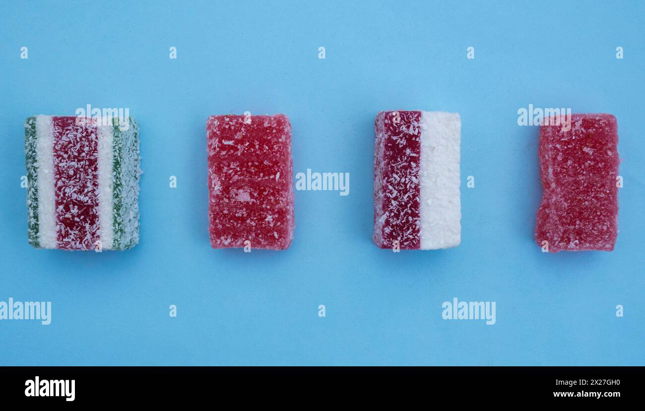 Four red gelatin candies on blue paper background. Flatlay of square ...