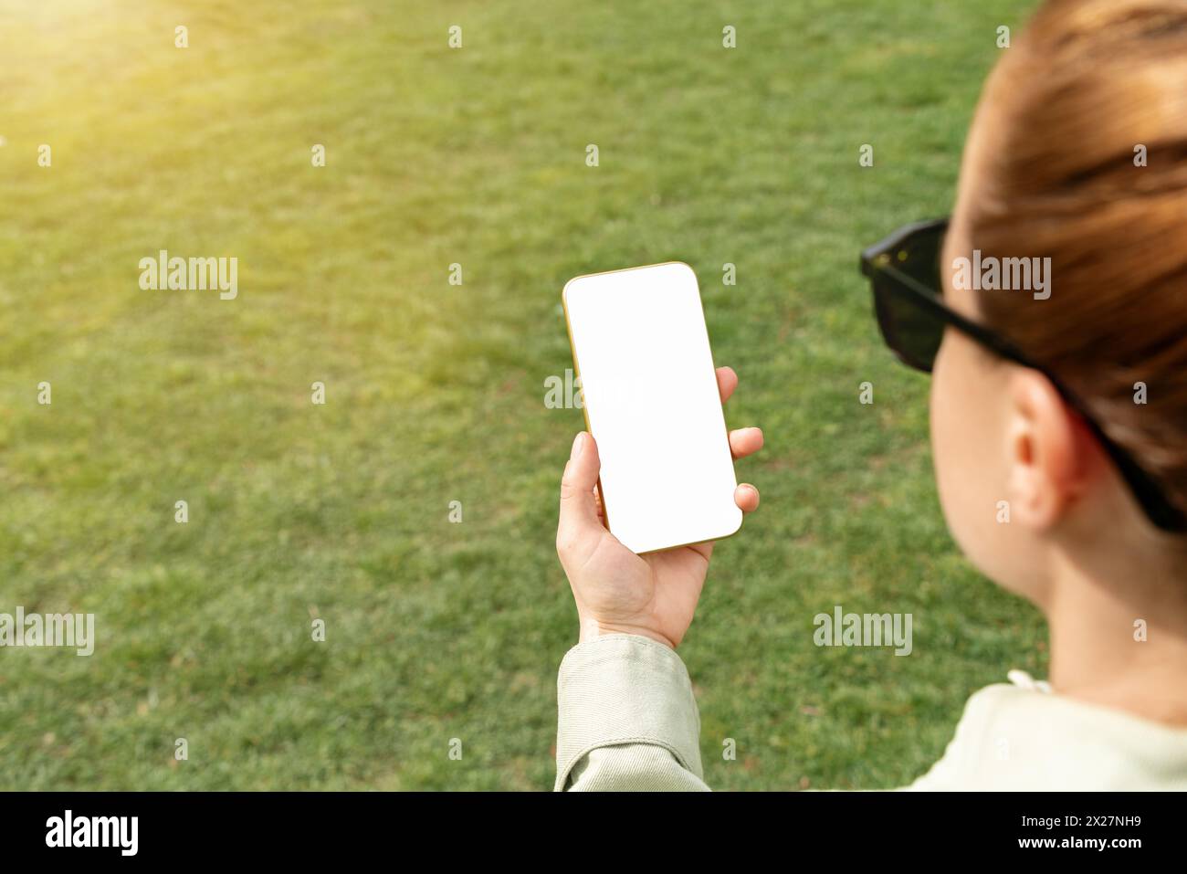 Woman holding smart phone with blank white screen in her hand against ...