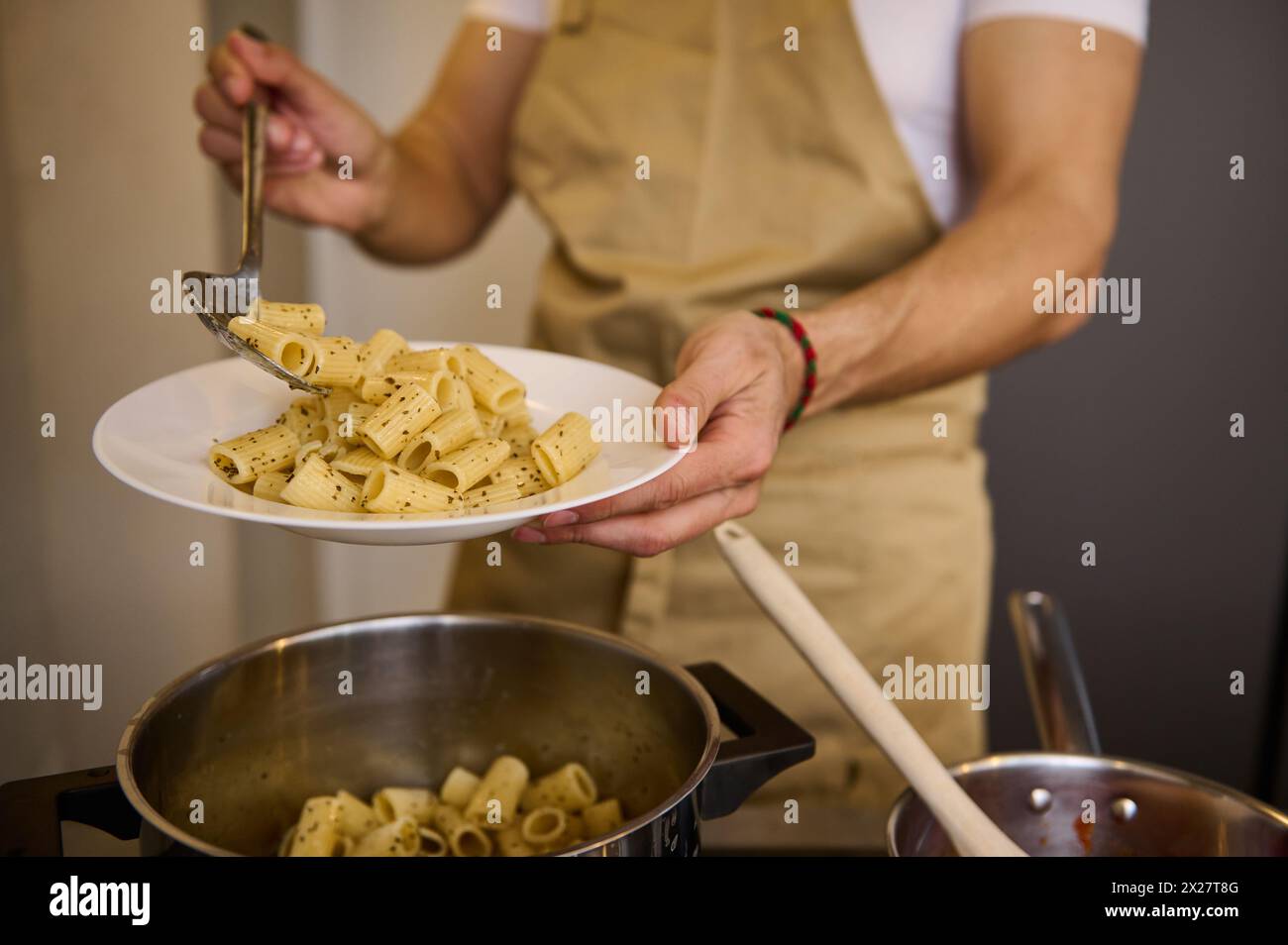 Close-up male chef pouring freshly cooked Italian past into a plate ...