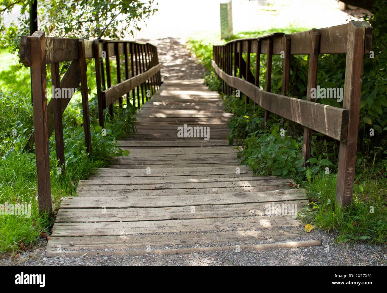 A plank staircase with a dark wooden railing leads down through shrubs ...