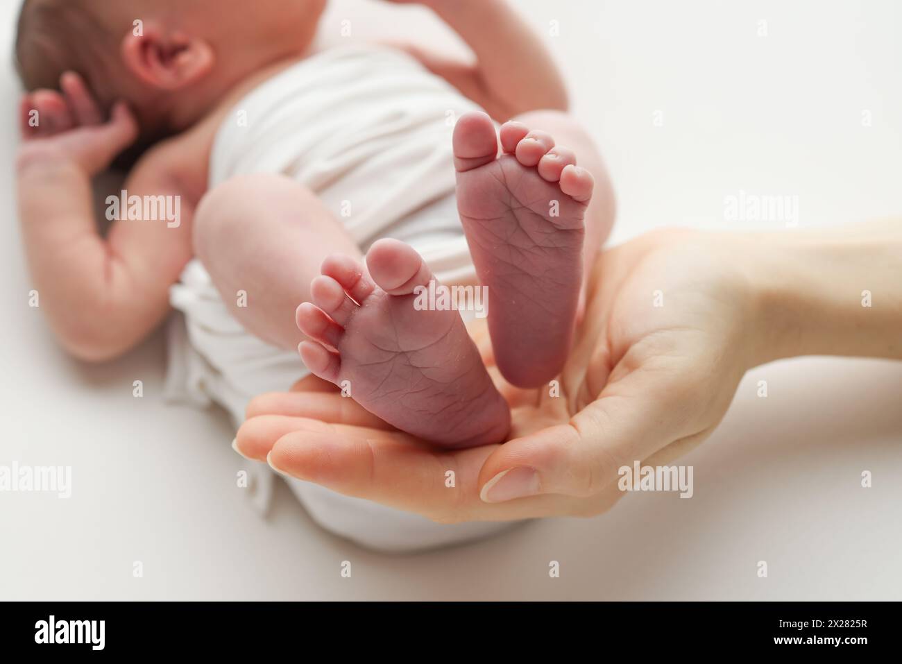 The palms of the father, the mother are holding the foot of the newborn ...