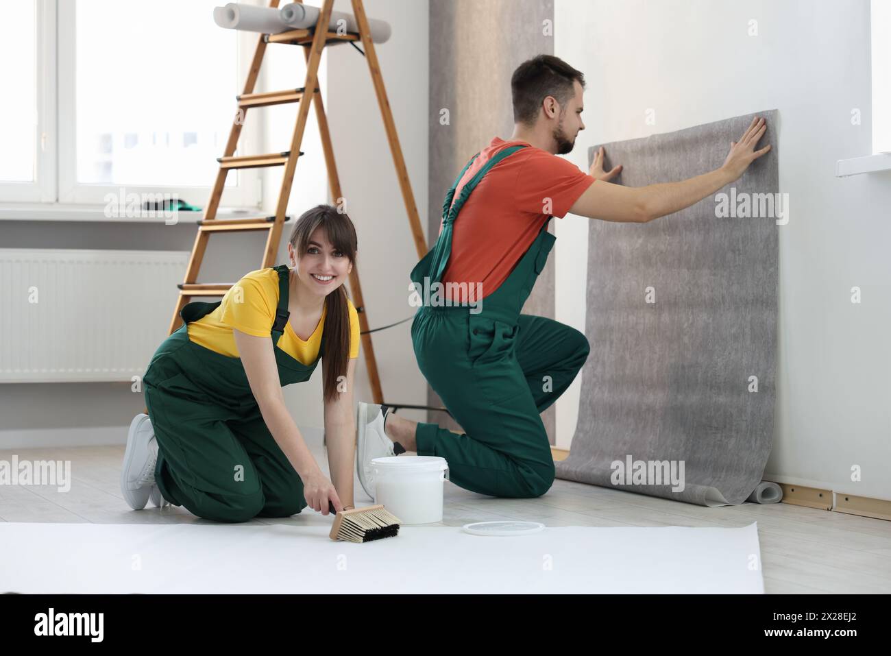 Workers hanging stylish gray wallpaper in room Stock Photo - Alamy