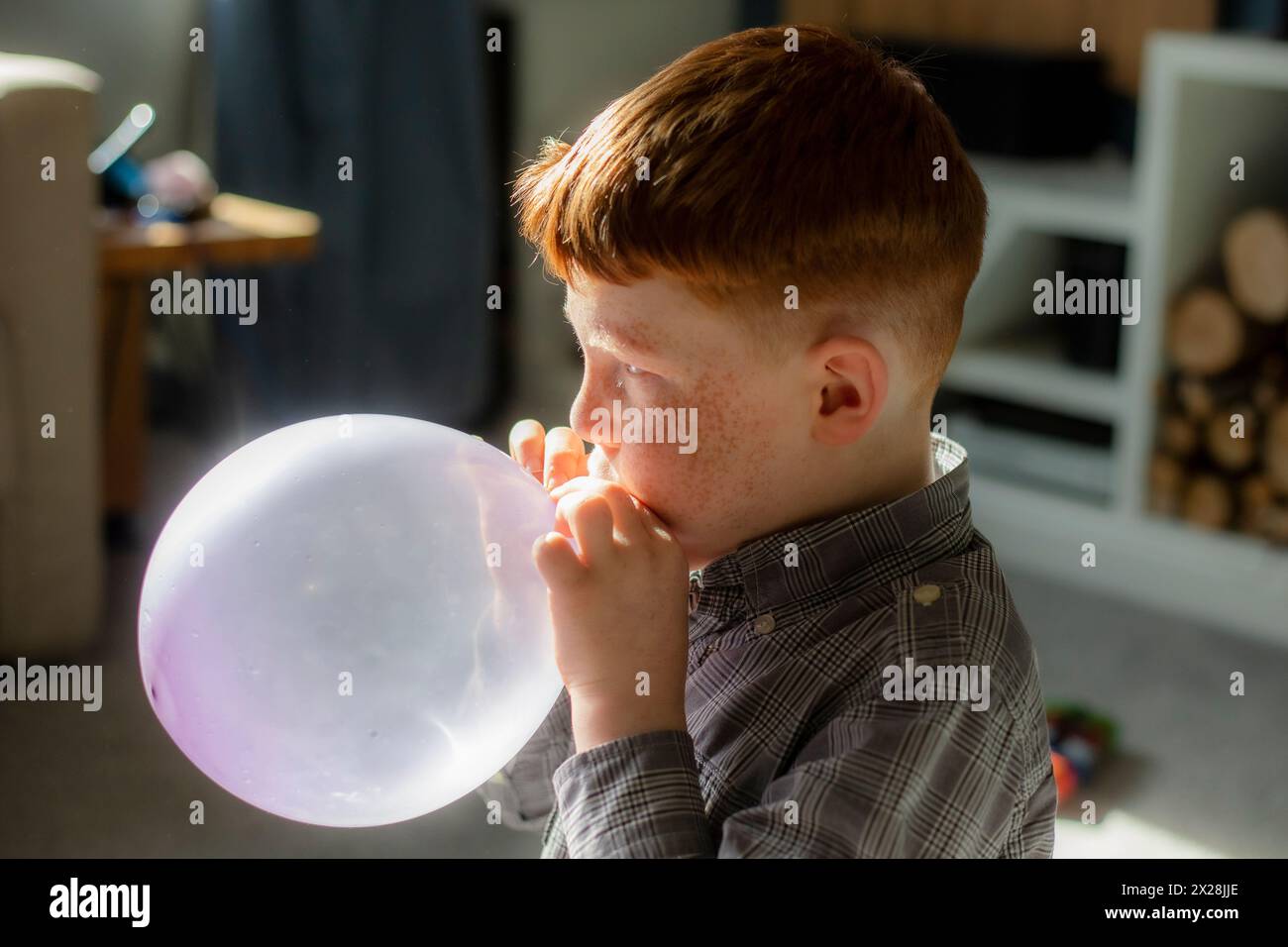 Young boy blowing up balloon Stock Photo - Alamy