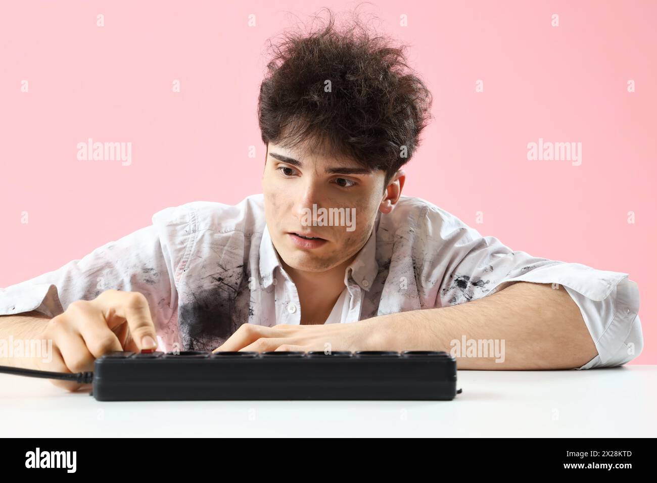 Electrocuted young man with burnt face and extension cord at table on ...