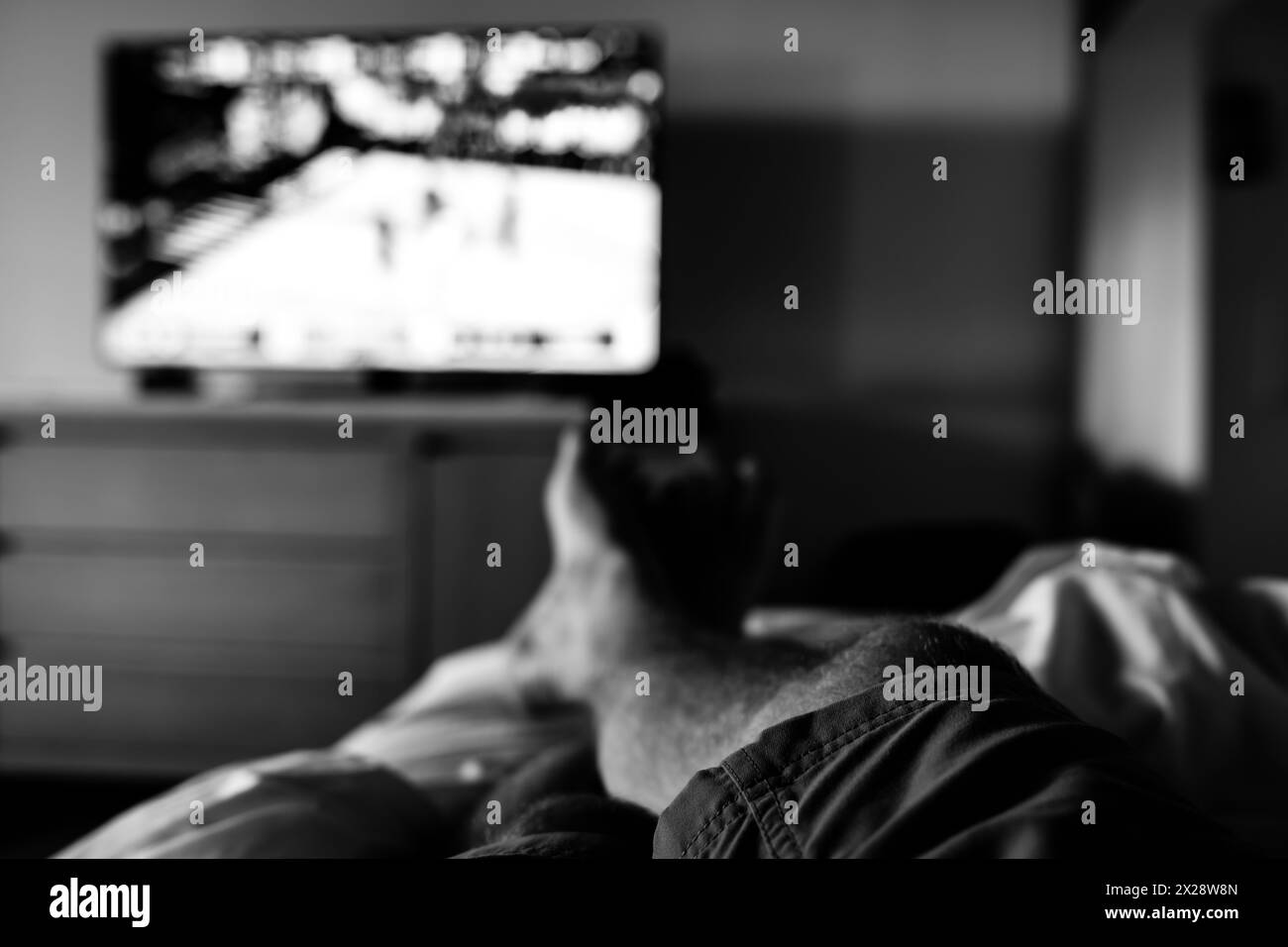 Selective focus on propped up feet with a blurred basketball game on ...