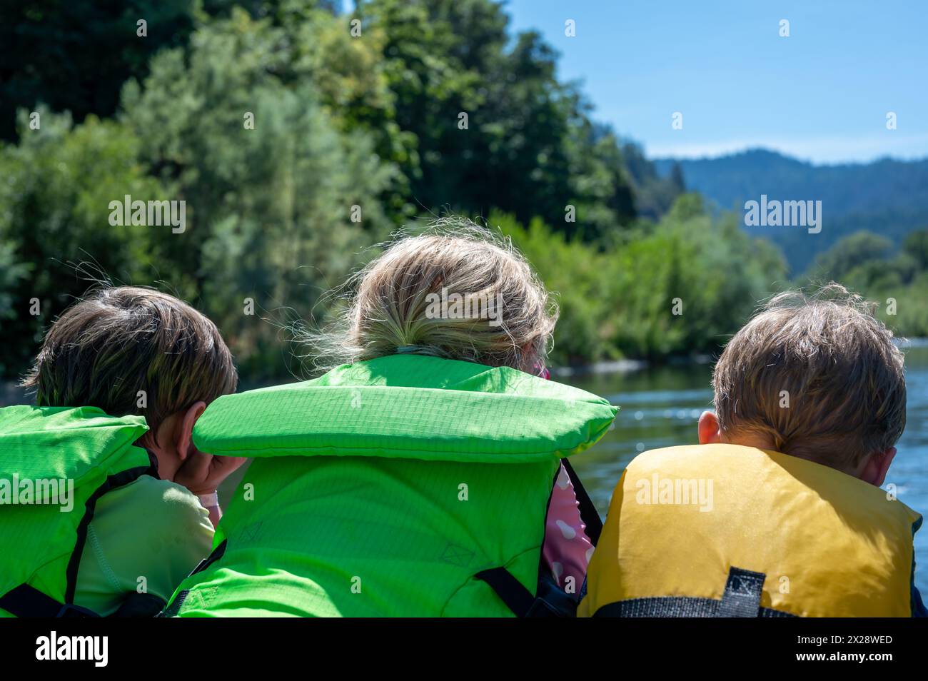 Selective focus on three children peering over a raft going down the ...