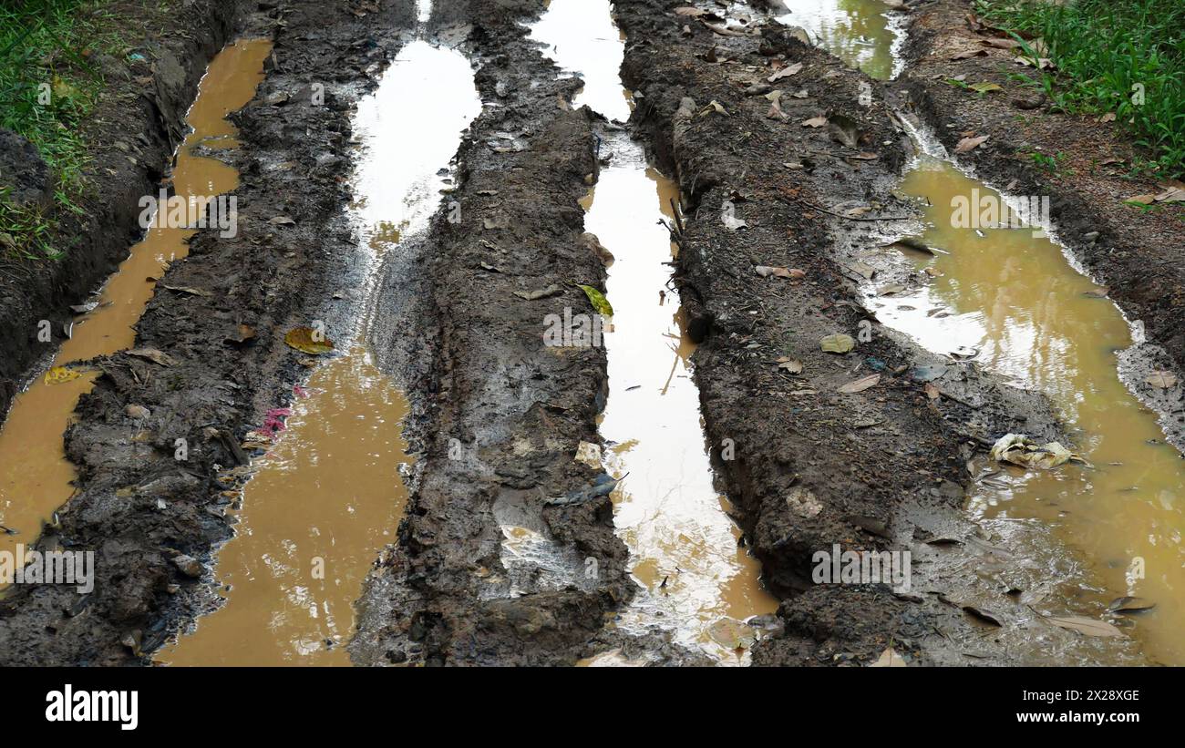 Road in forestry with muddy ruts with water and puddles in rural area ...