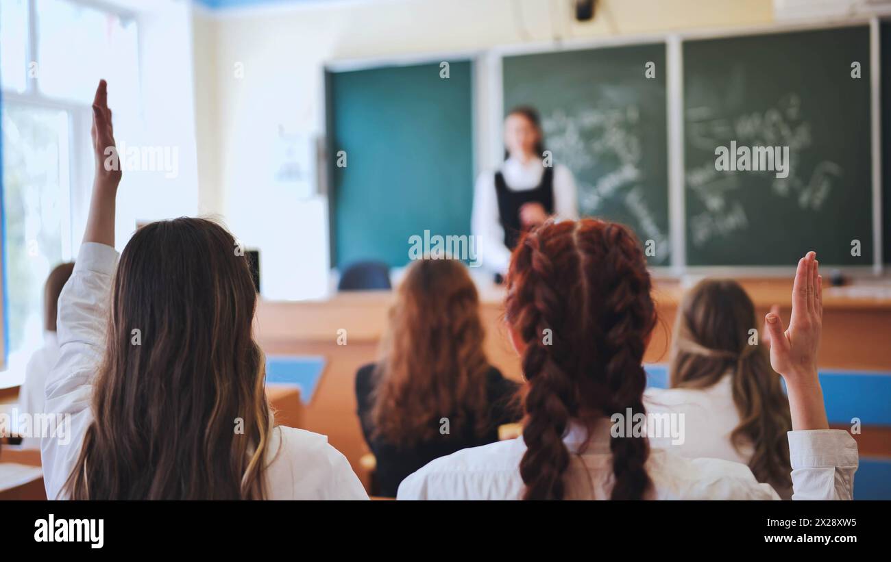 Intelligent group of young school children all raising their hands in ...