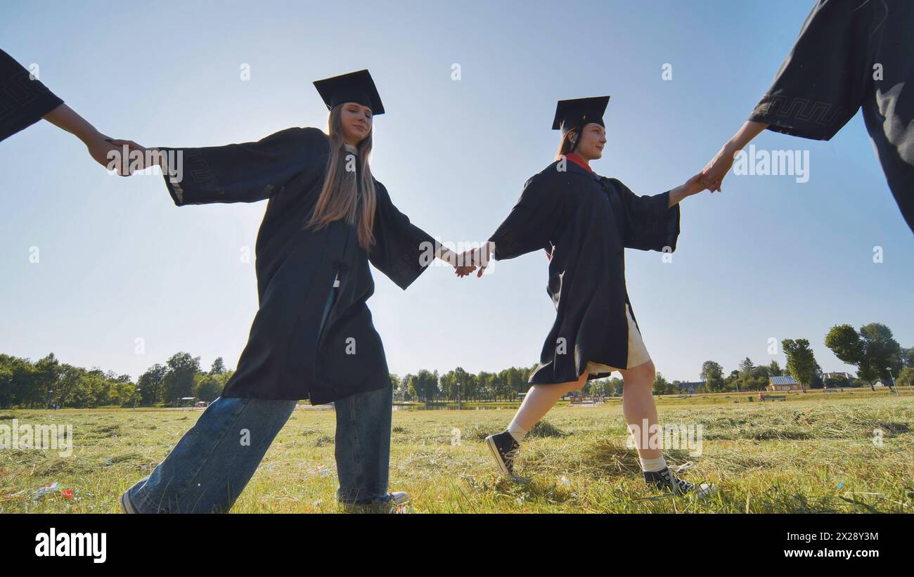 College graduates holding hands run in a round dance Stock Photo - Alamy