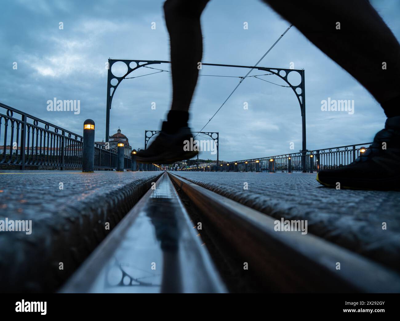 Silhouette of man's legs taking a step to cross the Porto metro track ...