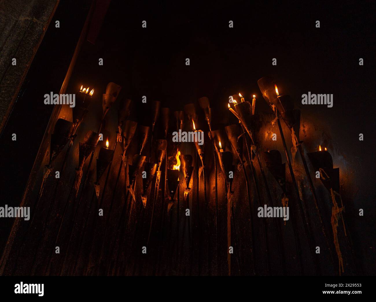Torches with lit wax candles forming a gathering of people to pray and ...