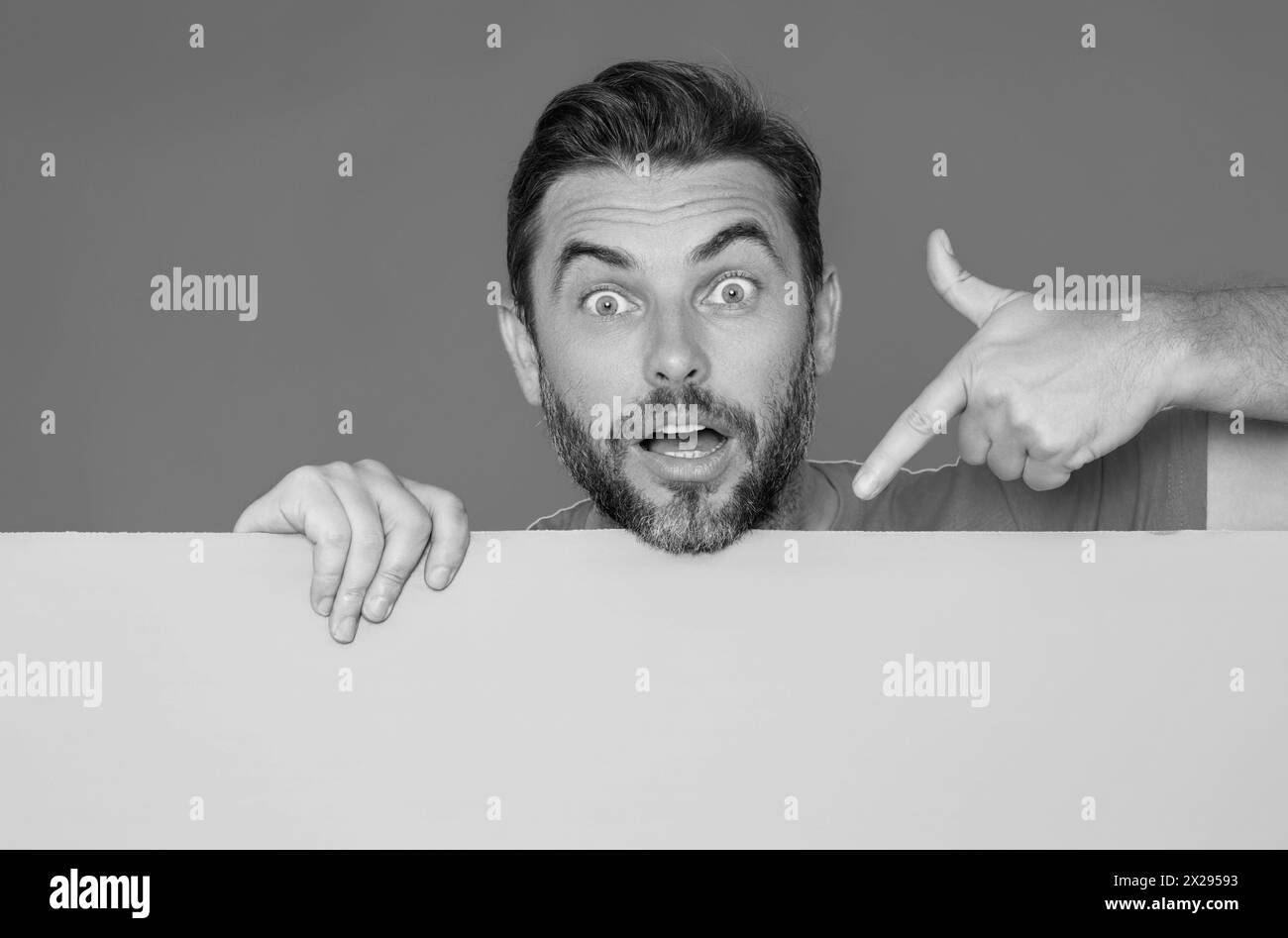 Handsome man holding empty board and pointing finger on board. Guy ...