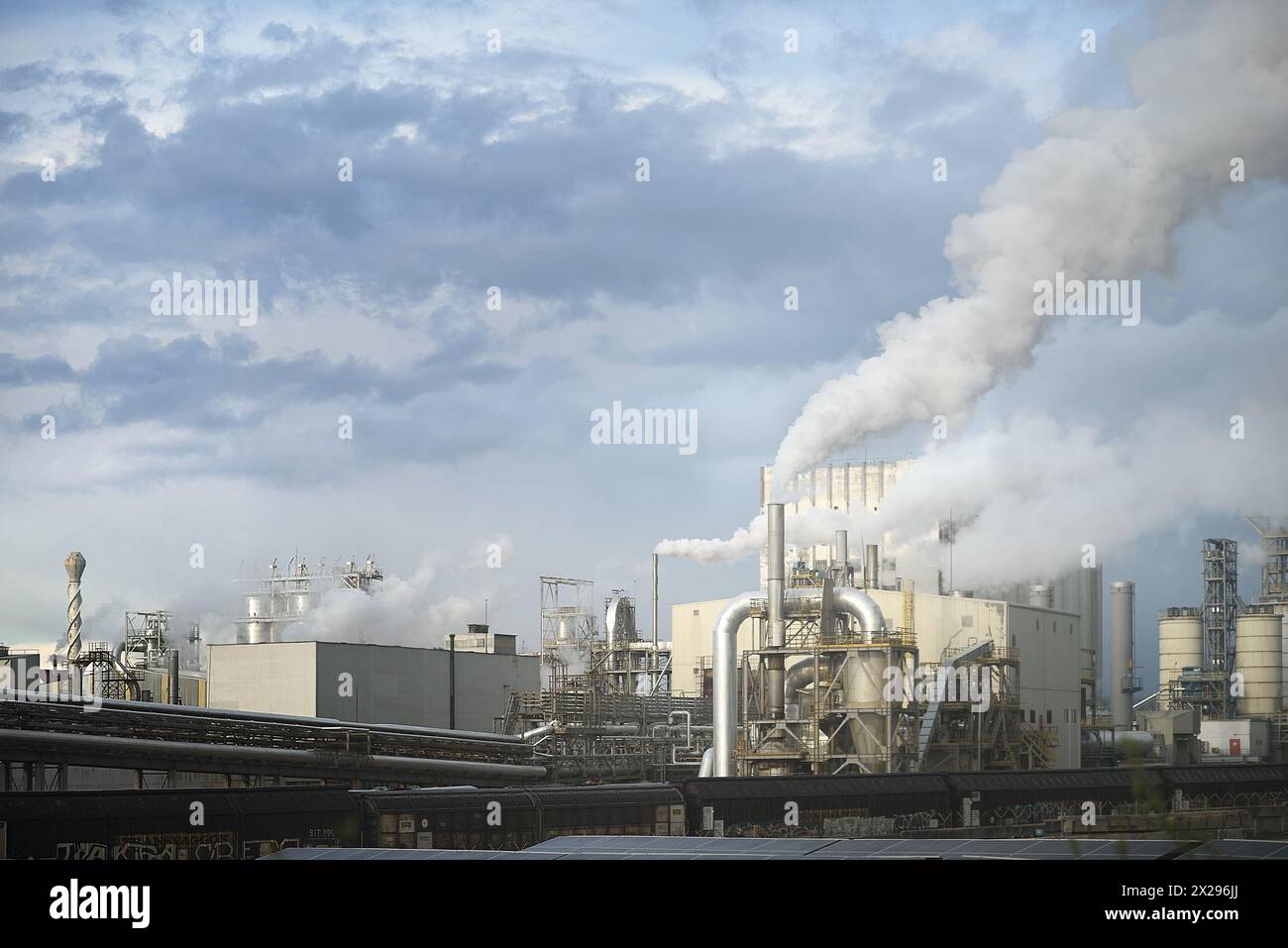 Industrial plant with tall smokestacks releasing steam or smoke into a ...