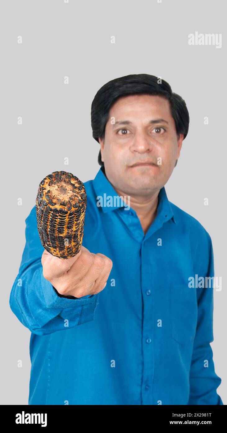 Portrait view of a young man offering to eat a corn cob with styles ...
