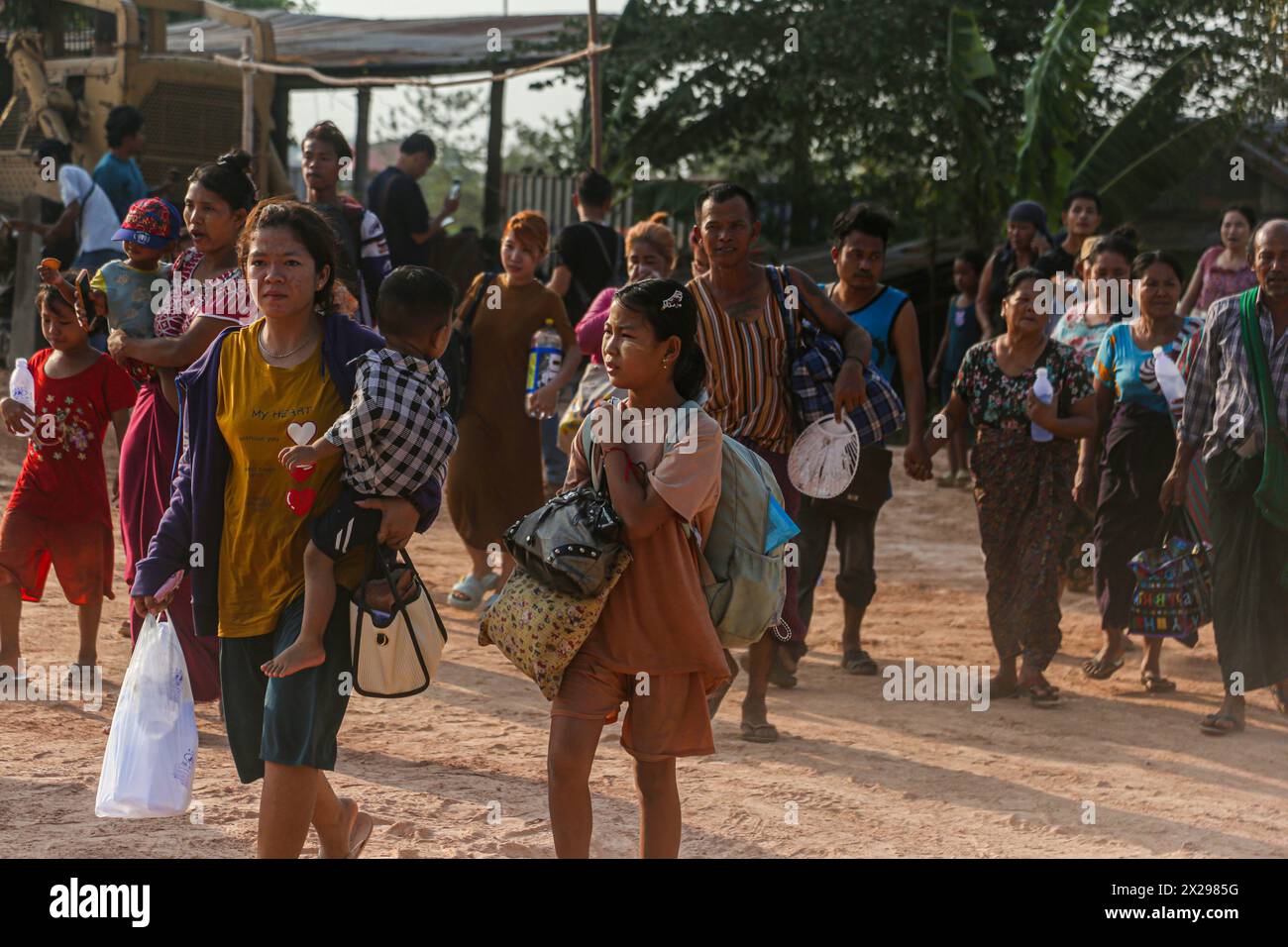 People carrying their bags arrive on the Thai side after they flee from ...